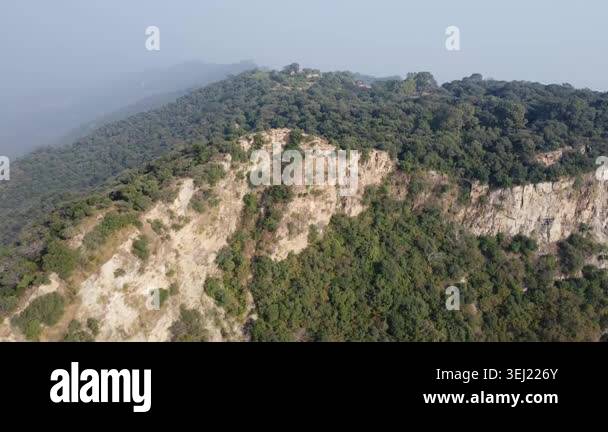 Tilla jogian ancient hilltop temple ruins visible above green forest in ...