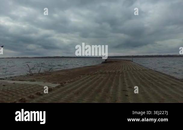 Atmospheric footage of rusty abandoned metal pier extending into dark ...
