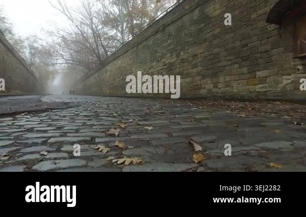 Old cobblestone road with stone walls and autumn fog creating ...
