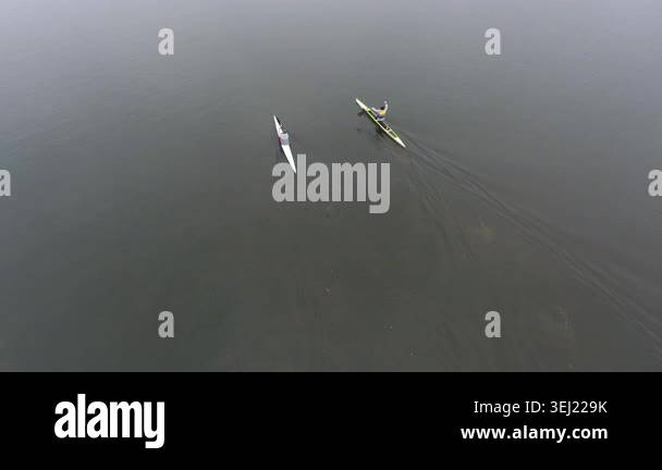 Aerial drone shot of two kayakers training on calm dark water with ...