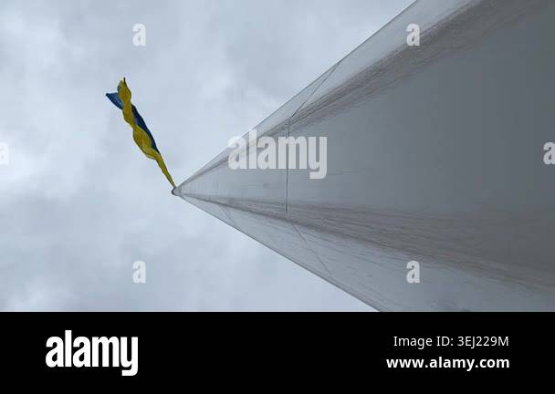 Blue and Yellow Ribbon Moving on Tall Flagpole Under Cloudy Overcast ...