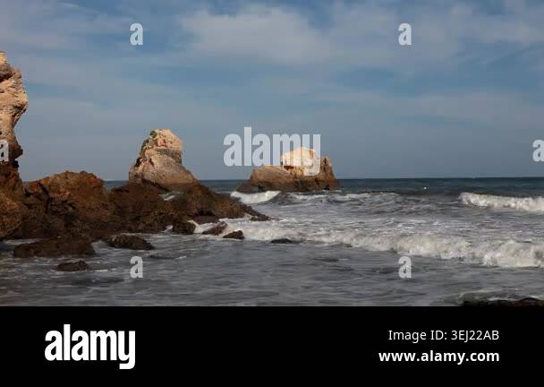 Rocky tidal shoreline with textured reef formations and gentle waves in ...