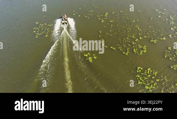 Drone aerial footage of a small boat crossing a wetland lake with ...