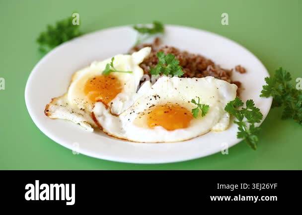 Fried eggs with buckwheat and parsley on white plate Stock Video ...