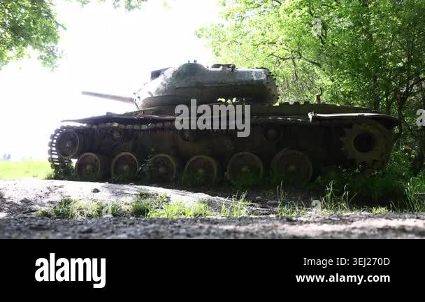 An abandoned, rusted tank stands in a forested area as a historic ...