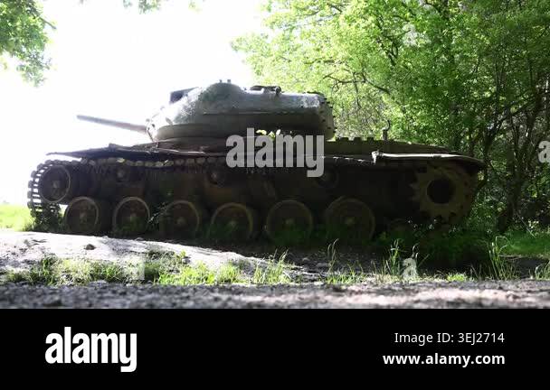 An abandoned, rusted tank stands in a forested area as a historic ...