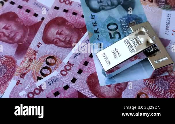 A silver bar, white metal against a backdrop of Chinese money, as a ...