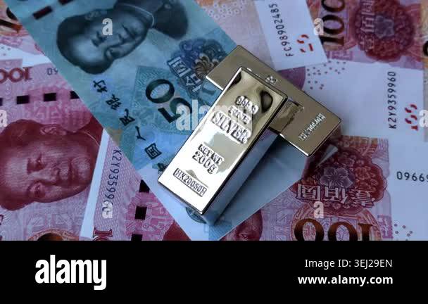 A silver bar, white metal against a backdrop of Chinese money, as a ...