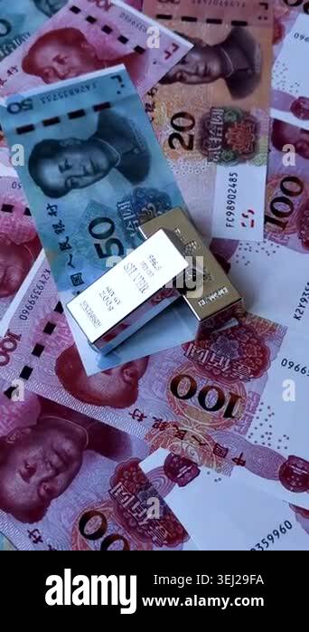 A silver bar, white metal against a backdrop of Chinese money, as a ...