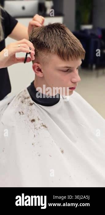 teenage boy lying back at barbershop sink getting hair rinsed with ...