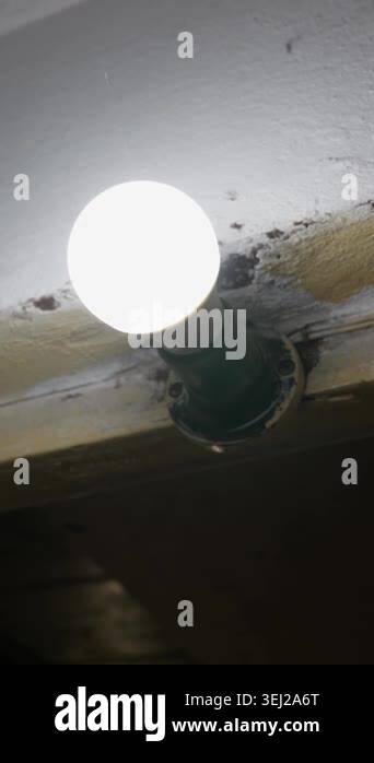 A bright round LED lightbulb glows intensely from a vintage green ...