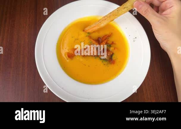 Hand Dipping a Toasted Breadstick into Creamy Roasted Pumpkin Soup for ...