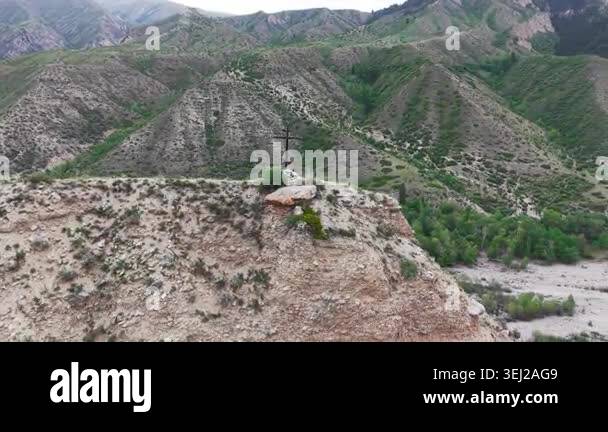 Drone aerial view circling an iron cross on top of a mountain with ...