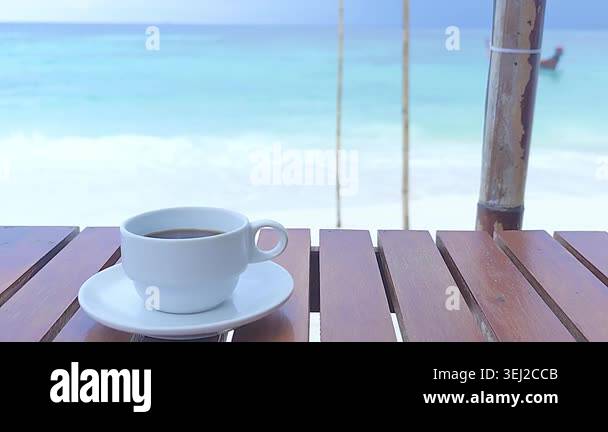 Relaxing seaside scene with a steaming coffee cup and soft ocean waves ...