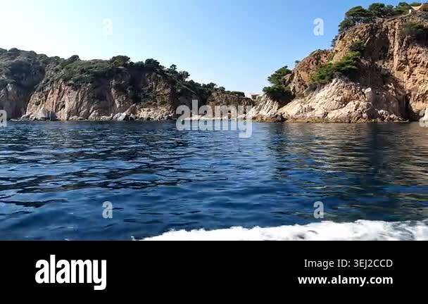 Moving boat view of a beautiful hidden cove with rocky cliffs and pine ...