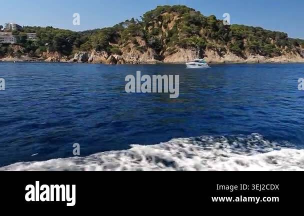 White wake of a fast boat sailing along the rocky coastal cliffs and ...