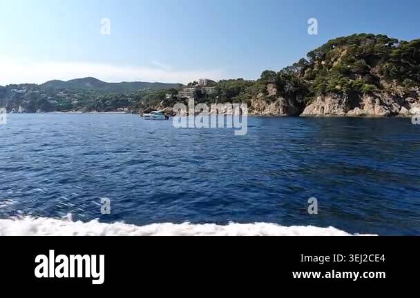 White wake of a fast boat sailing along the rocky coastal cliffs and ...