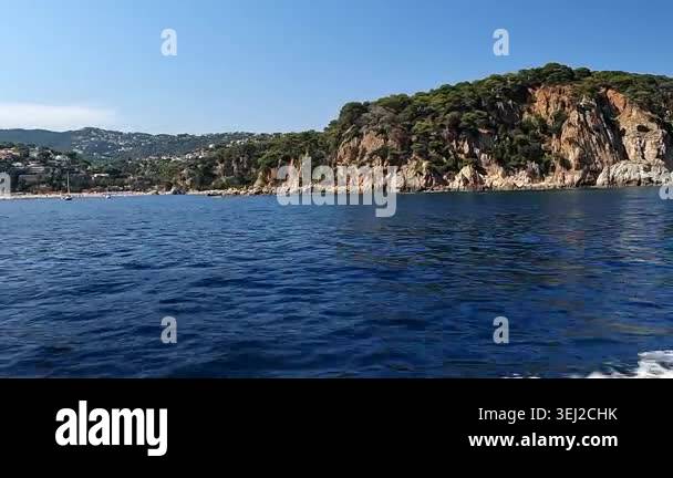 White wake of a fast boat sailing along the rocky coastal cliffs and ...