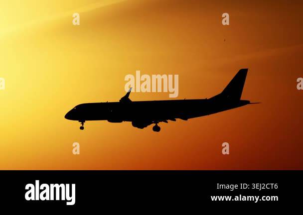 A plane approaches for landing as the sun sets in the background. The ...