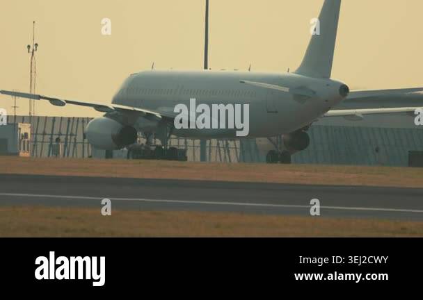 A plane sits on the runway at the airport as the sun sets. The ground ...