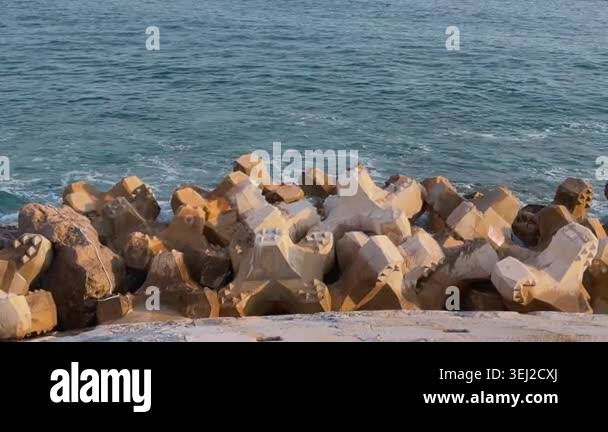 Yellow concrete tetrapod block forming protective breakwater barrier ...
