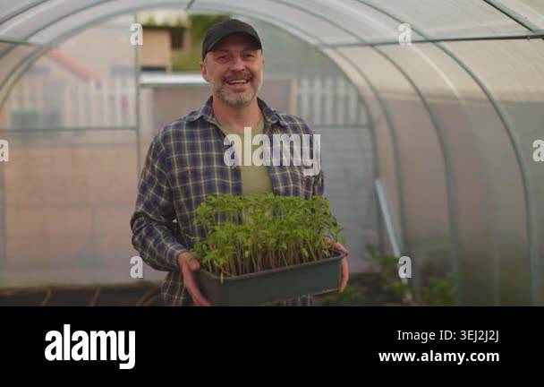 Medium shot of a happy male farmer wearing a cap and plaid shirt ...
