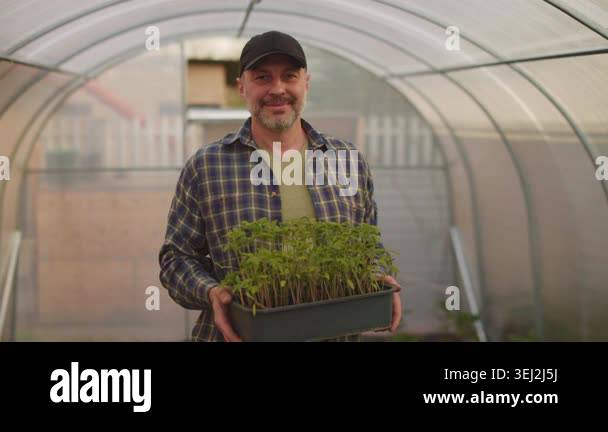 Medium shot of a happy male farmer wearing a cap and plaid shirt ...