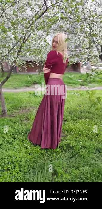 Blonde adult woman looks over her shoulder in a burgundy outfit among ...