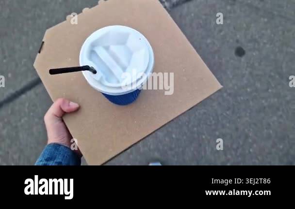 Hand holding pizza box and paper coffee cup on asphalt background ...