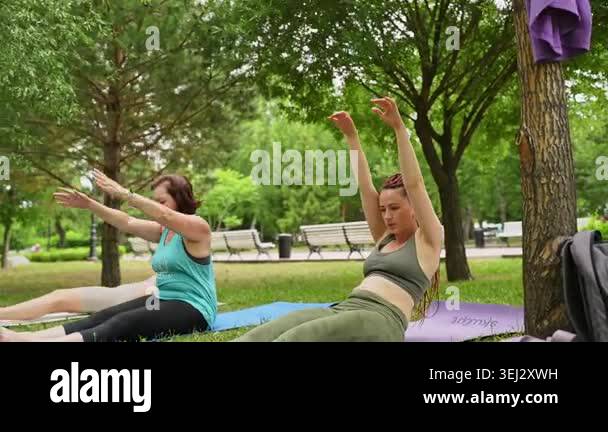 Group of women doing abdominal and core exercises on grass mats ...