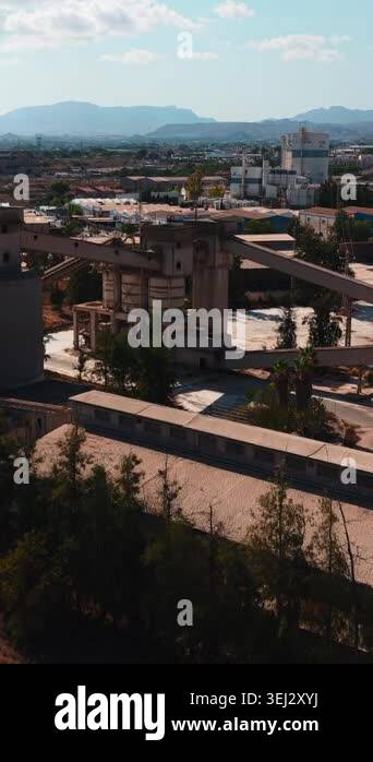 Drone footage slowly descending over a derelict cement plant in a ...