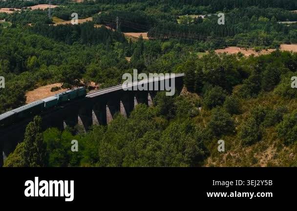 Scenic aerial view of a vintage train traveling on a stone bridge ...