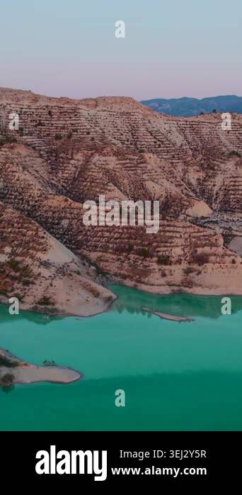 Aerial view of a stunning turquoise lake surrounded by dry, terraced ...