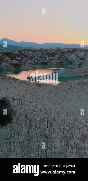 Aerial view flying backward over a turquoise reservoir with eroded ...