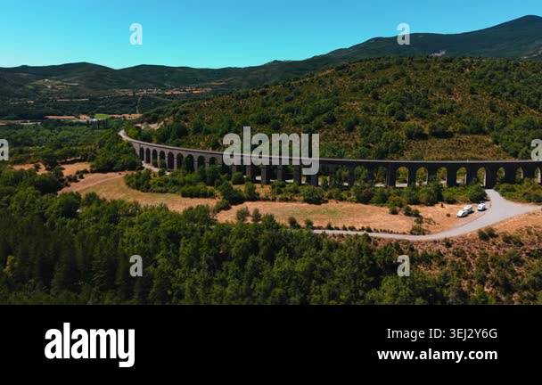 Old abandoned stone railway viaduct crossing a lush green mountain ...