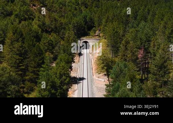 High angle view following an empty railway leading to a dark tunnel ...