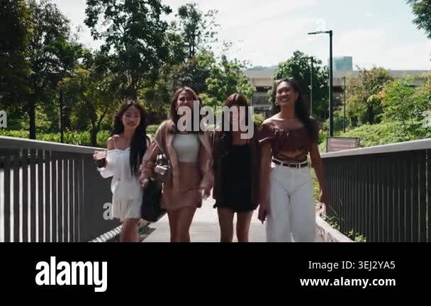 Group of four happy asian women walking on a bridge in bangkok, filming ...