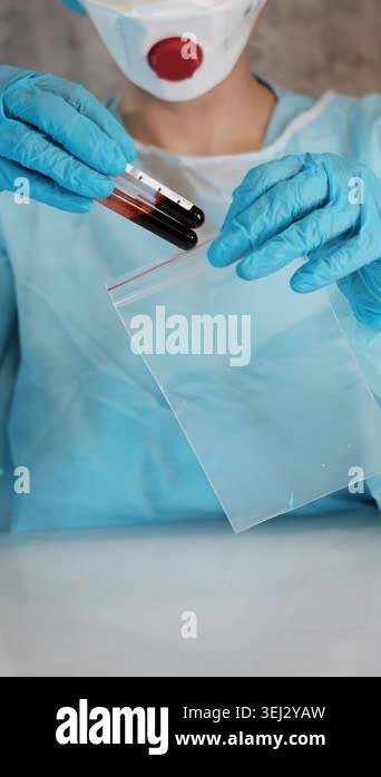 Medical professional in protective equipment placing blood sample tube ...