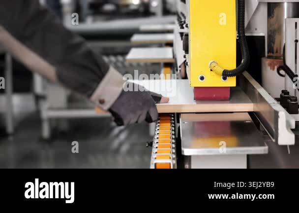Worker feeding a laminated wood panel into an industrial woodworking ...