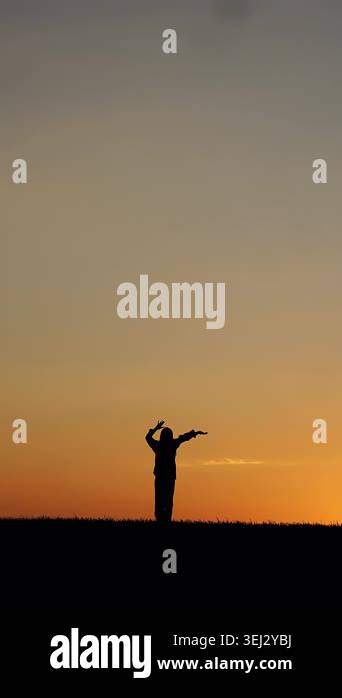 Silhouette of happy girl raising hands and enjoying sunset outdoors ...