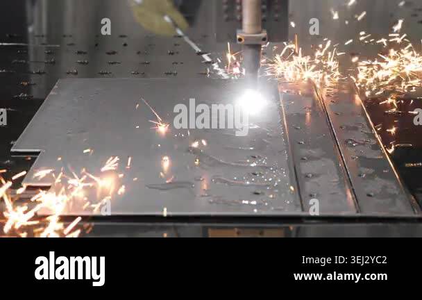 Automated CNC plasma cutting machine cutting metal sheet with sparks in ...