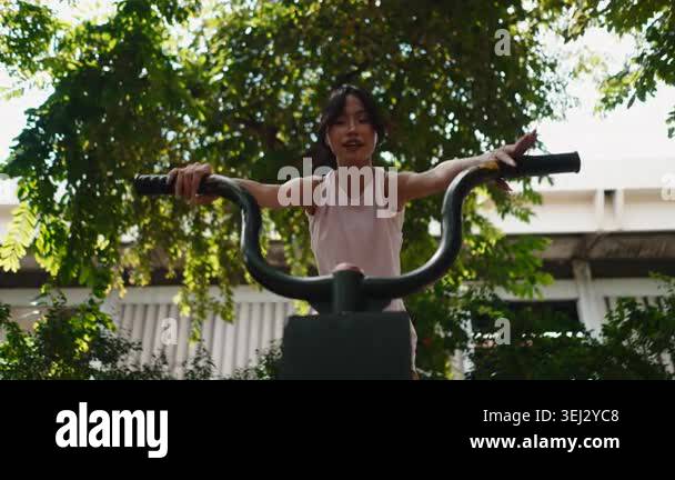 Young asian woman working out in an outdoor gym, focusing on her upper ...