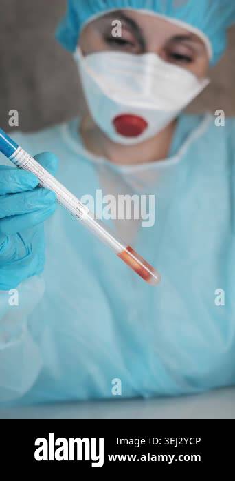 Laboratory worker in protective equipment holding blood sample tube for ...