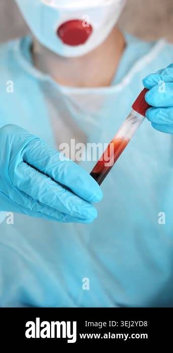 Medical professional in protective equipment holding blood sample tube ...