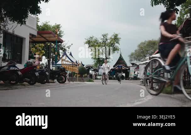 Group of happy young friends cycling on a quiet street in a traditional ...