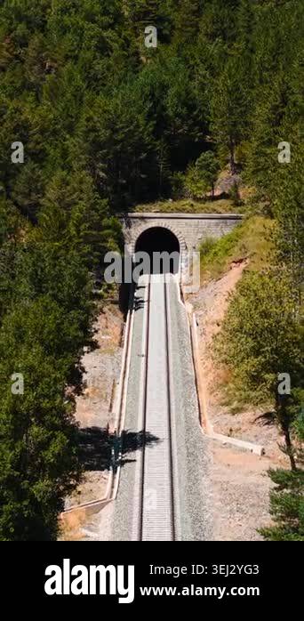 High angle drone view of railroad tracks disappearing into a dark stone ...
