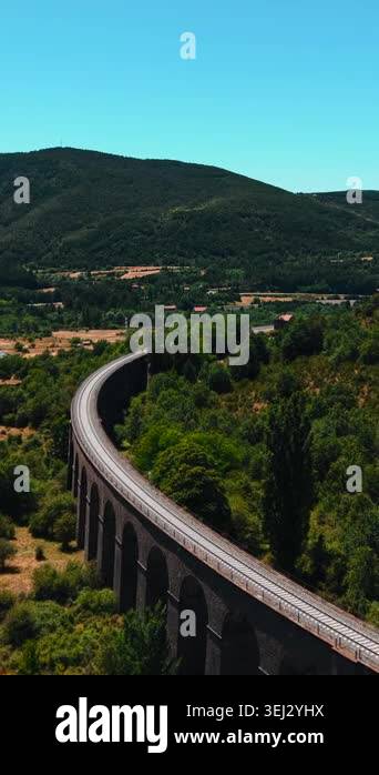 Aerial perspective of an old stone railway bridge crossing a green ...