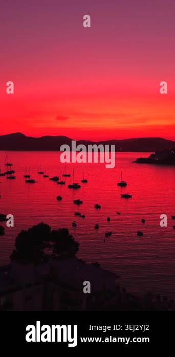 Beautiful bay with boats and yachts silhouetted against a stunning red ...