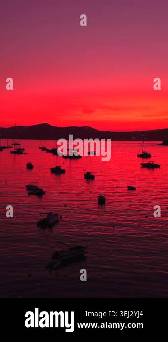 Vivid red and purple sunset sky reflecting on the calm sea with ...