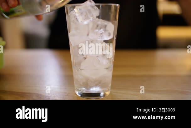 Preparing ice drink. Bartender work. Hand pouring sparkling water from ...